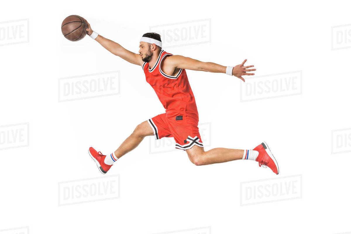 Side view of young sportsman playing basketball isolated on white ...