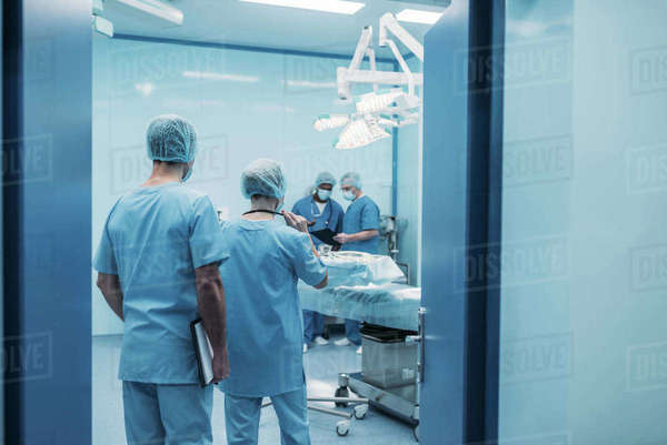 Rear view of multicultural surgeons in operating room - Royalty-free ...