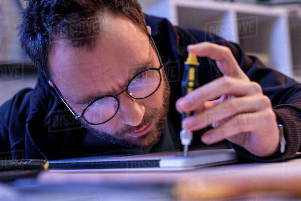 Caucasian man using screwdriver while fixing digital tablet - Stock ...