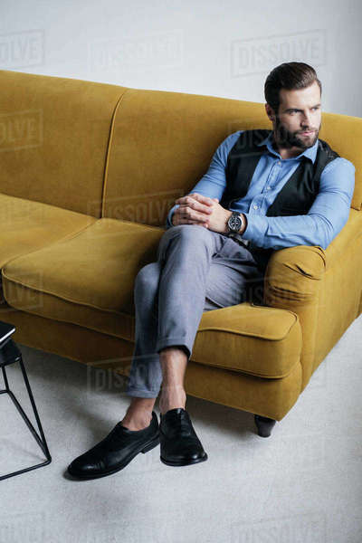 Stylish man sitting on yellow sofa - Royalty-free Stock Photo | Dissolve