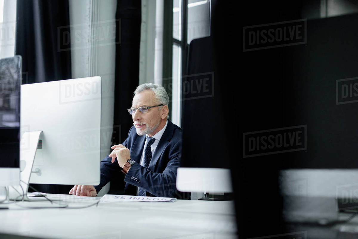 Selective focus of senior businessman working on computer in office ...