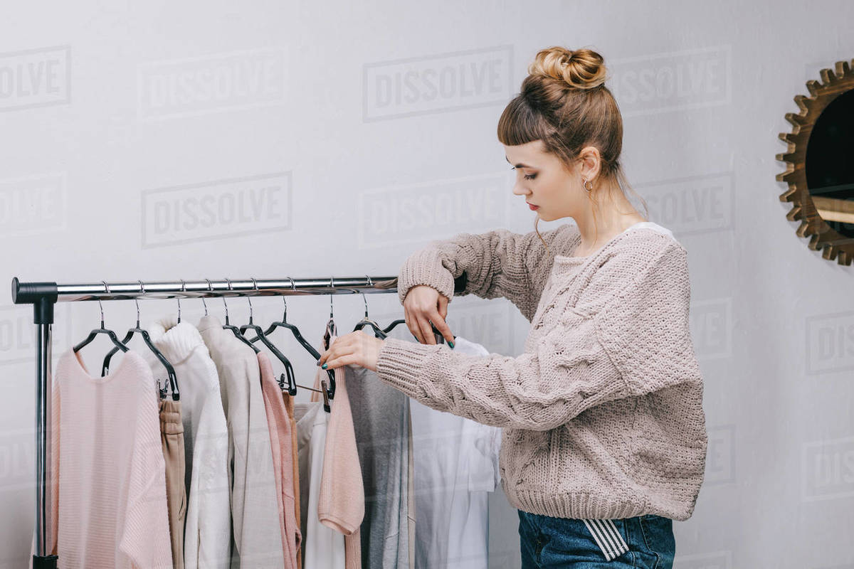 Side view of girl standing near stand and choosing what to wear - Stock ...