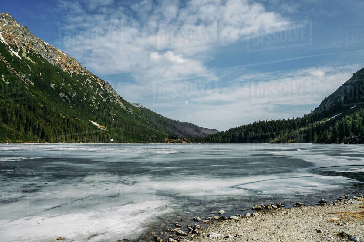 View of lake with ice on surface and mountains on background, Morskie ...