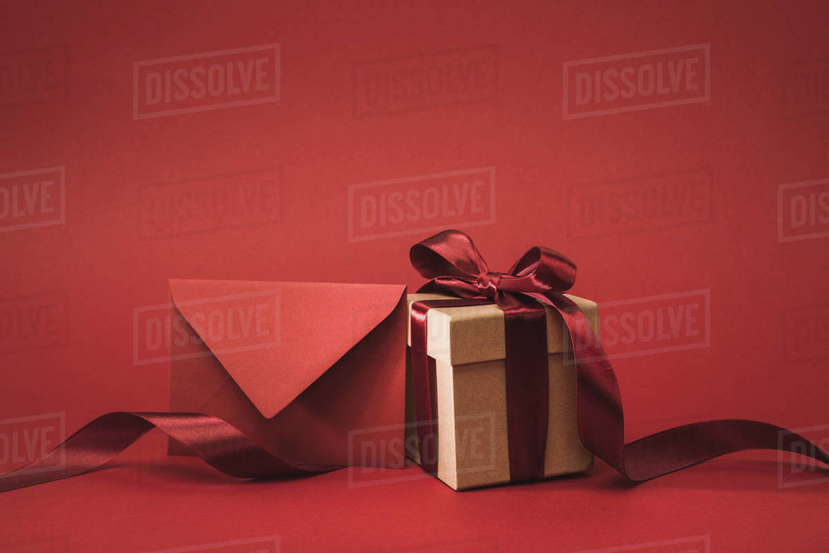 Close up view of empty envelope and present with ribbon isolated on red ...