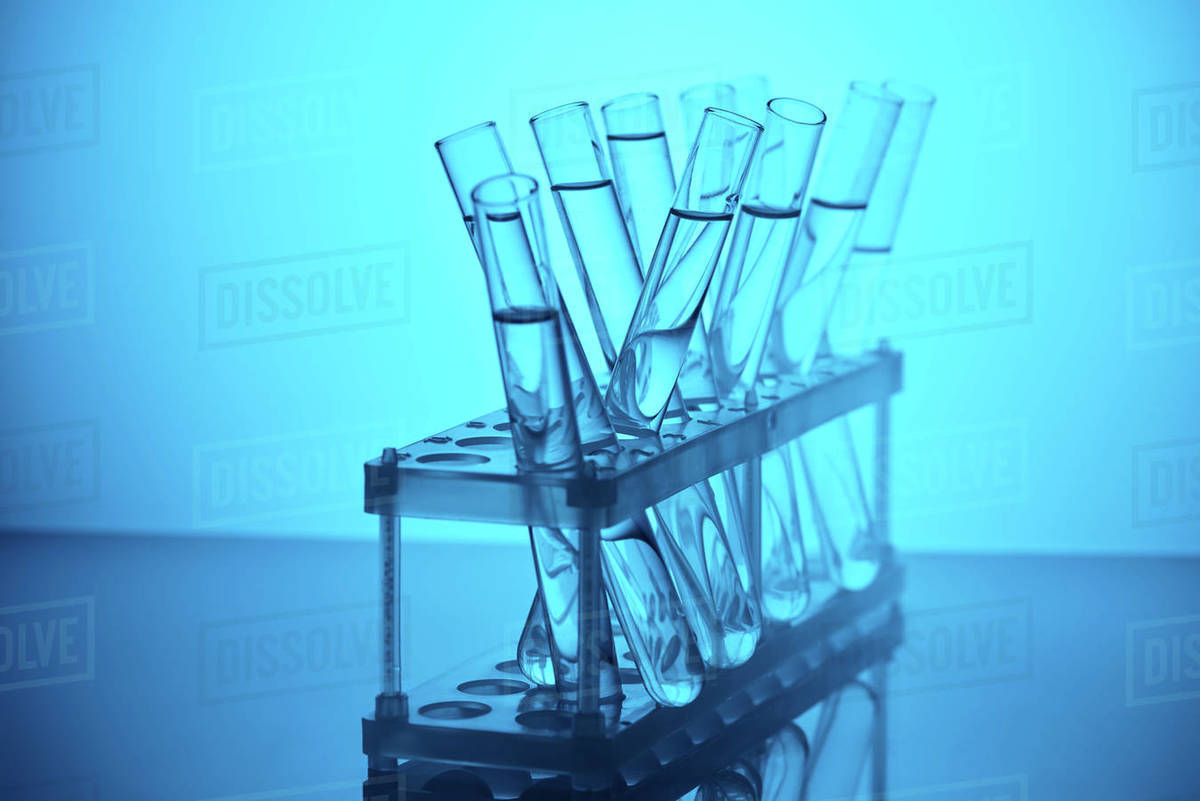 Glass tubes with liquid on stand for chemical analysis on blue ...