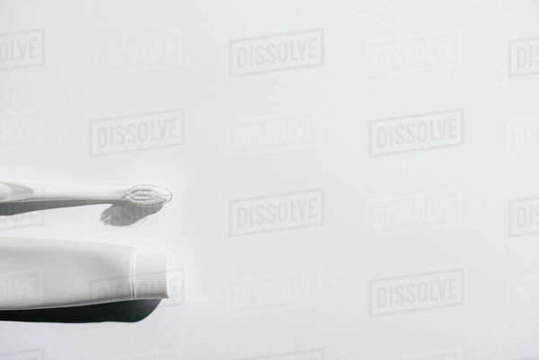 Top view of white toothbrush and toothpaste, on white with copy space ...
