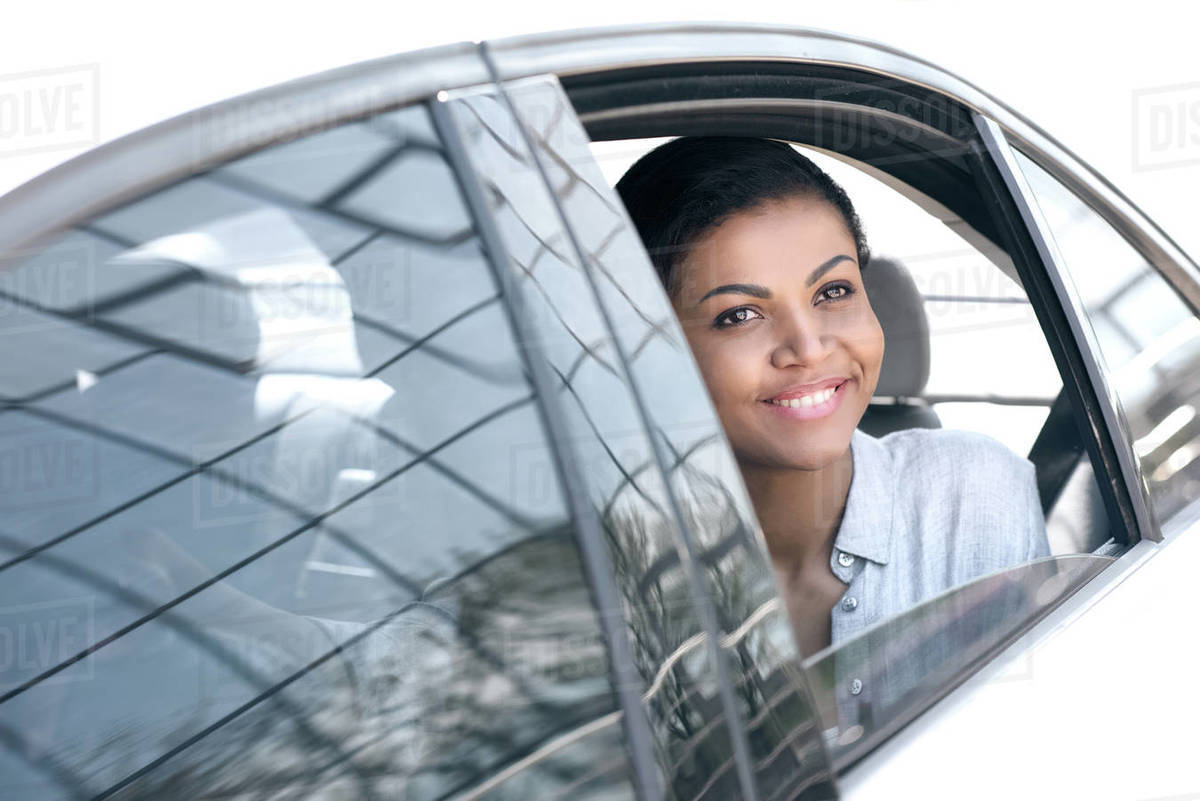 Beautiful young smiling woman looking through car window - Stock Photo ...