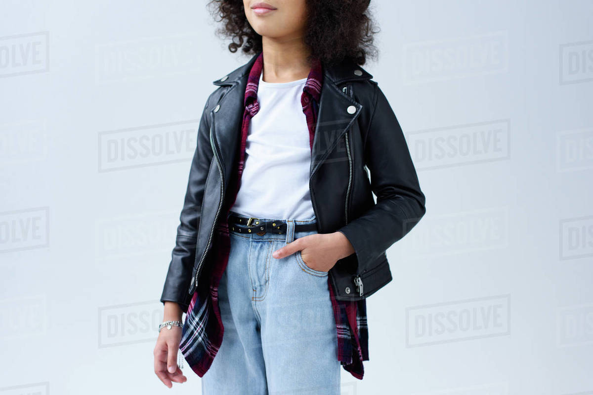 Cropped shot of stylish little child in leather jacket isolated on grey ...