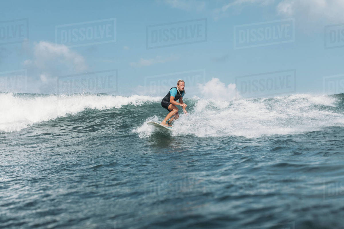 Surfer riding wave on board in ocean - Royalty-free Stock Photo | Dissolve