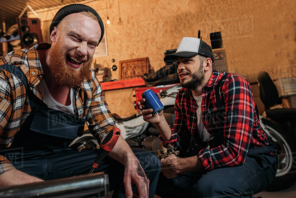 Laughing young mechanics having break in work at garage - Royalty-free ...