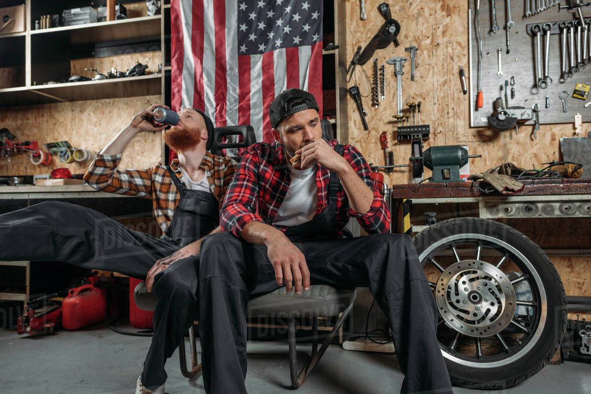 Exhausted mechanics having lunch together at garage - Royalty-free ...