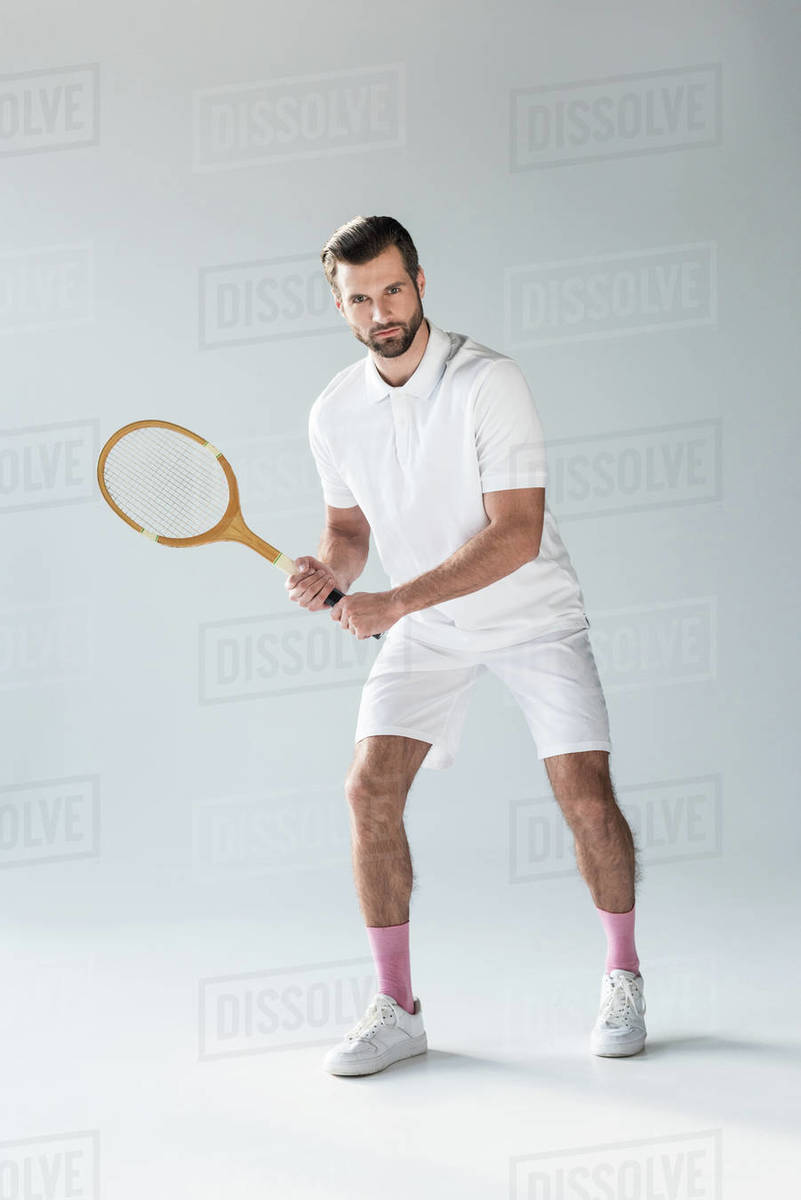 Handsome tennis player with tennis racket looking at camera on grey ...