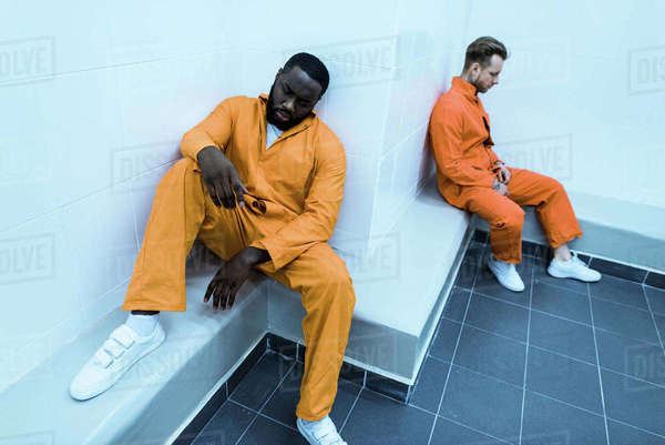 High angle view of multicultural prisoners sitting on benches in prison ...