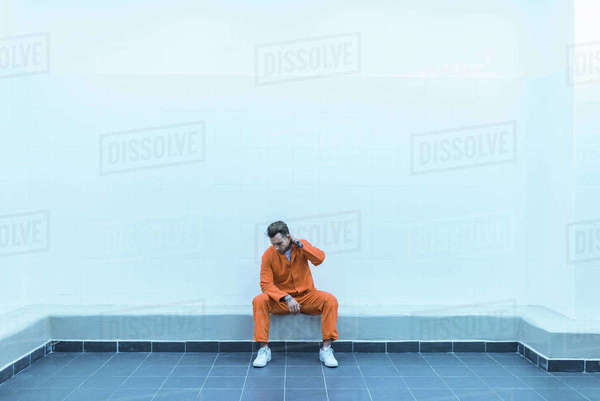 Prisoner sitting on bench in prison cell - Royalty-free Stock Photo ...