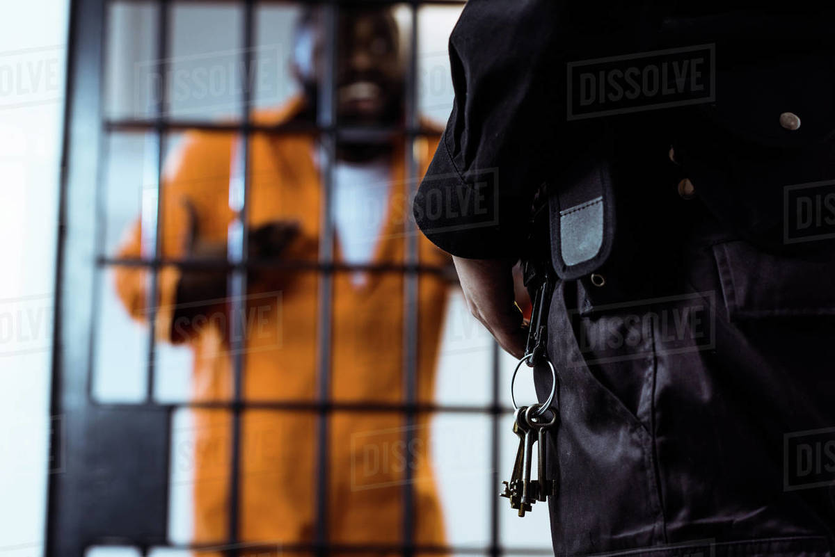 Cropped image of security guard standing near prison bars with keys ...