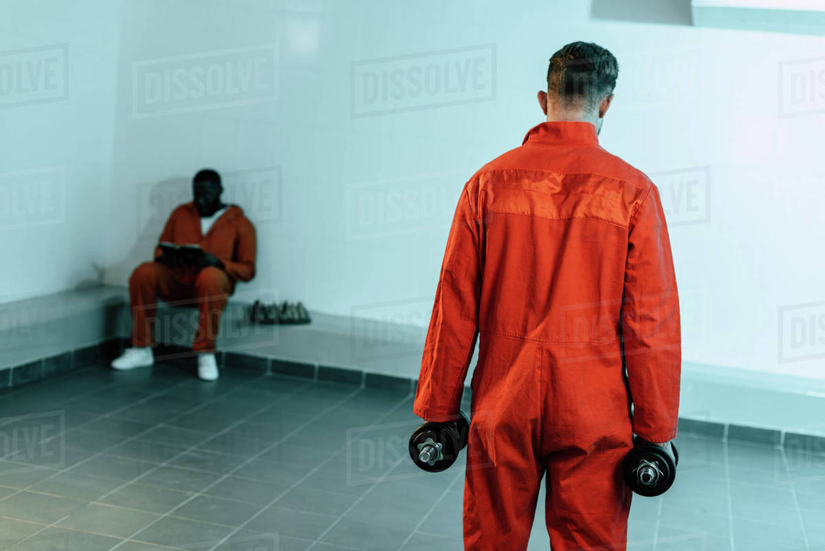 rear view of prisoner training with dumbbells in prison cell - Royalty ...
