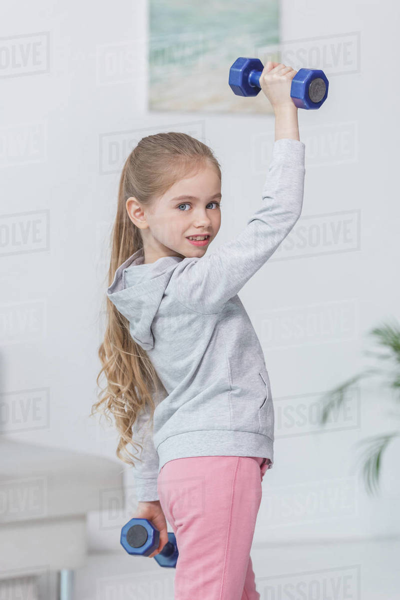 Beautiful little child working out with dumbbells - Stock Photo - Dissolve