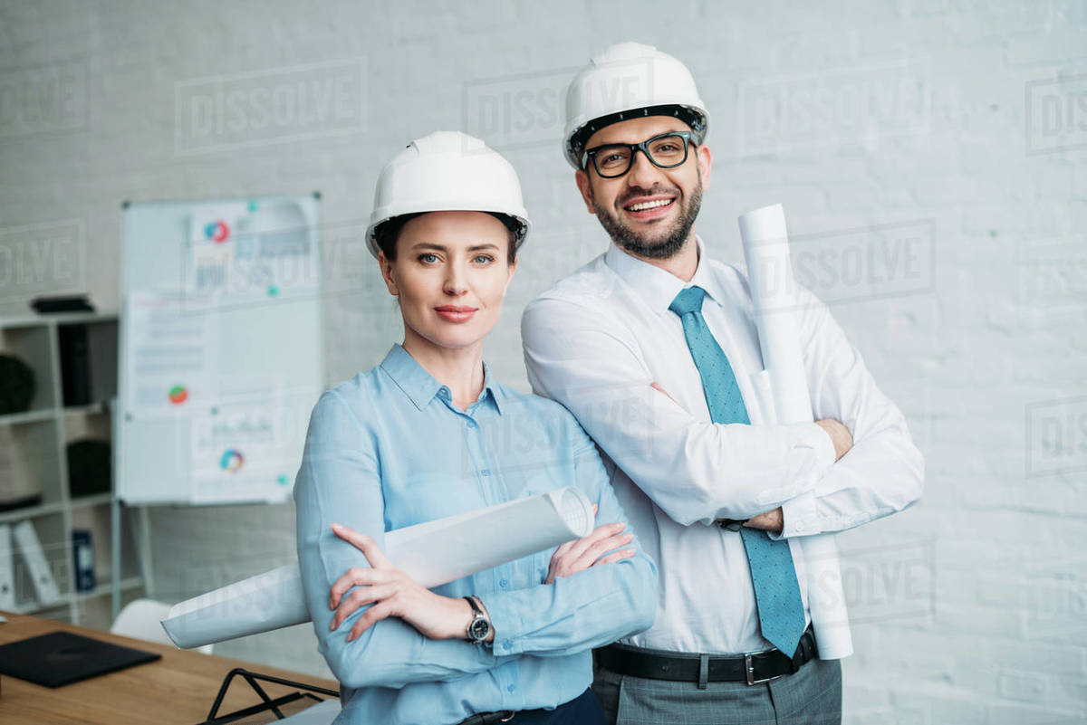 Happy architects standing at modern office with building plans ...