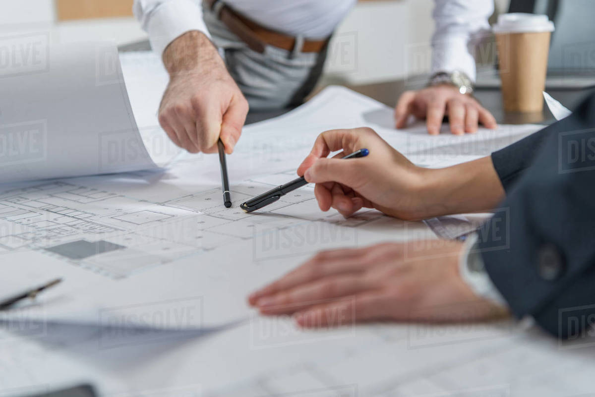 Cropped shot of architects working with building plans together at ...
