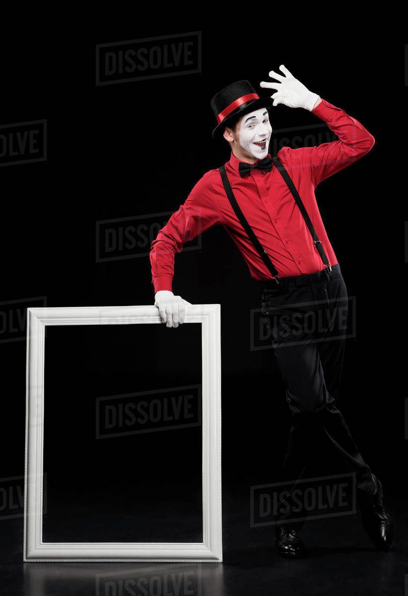 Happy mime leaning on frame and waving hand isolated on black - Royalty ...
