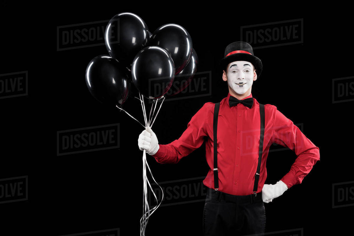Mime holding bundle of black balloons isolated on black - Stock Photo ...