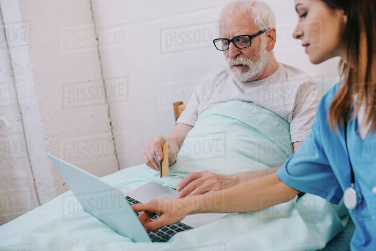 Nurse helping senior patient using laptop and credit card - Stock Photo ...
