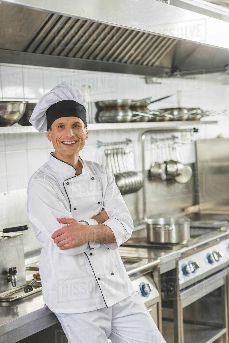 Smiling chef standing with crossed arms and looking at camera at ...