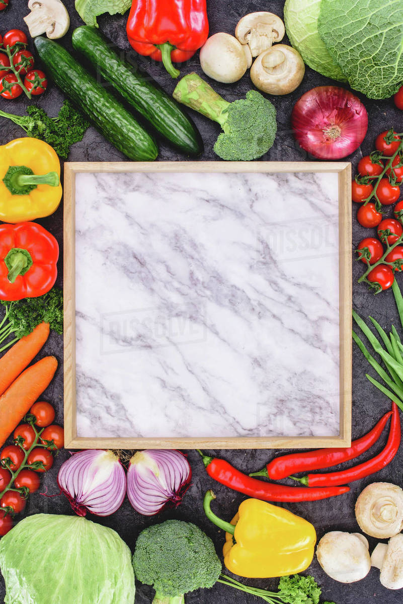 Top view of fresh raw vegetables and blank marble board on black ...