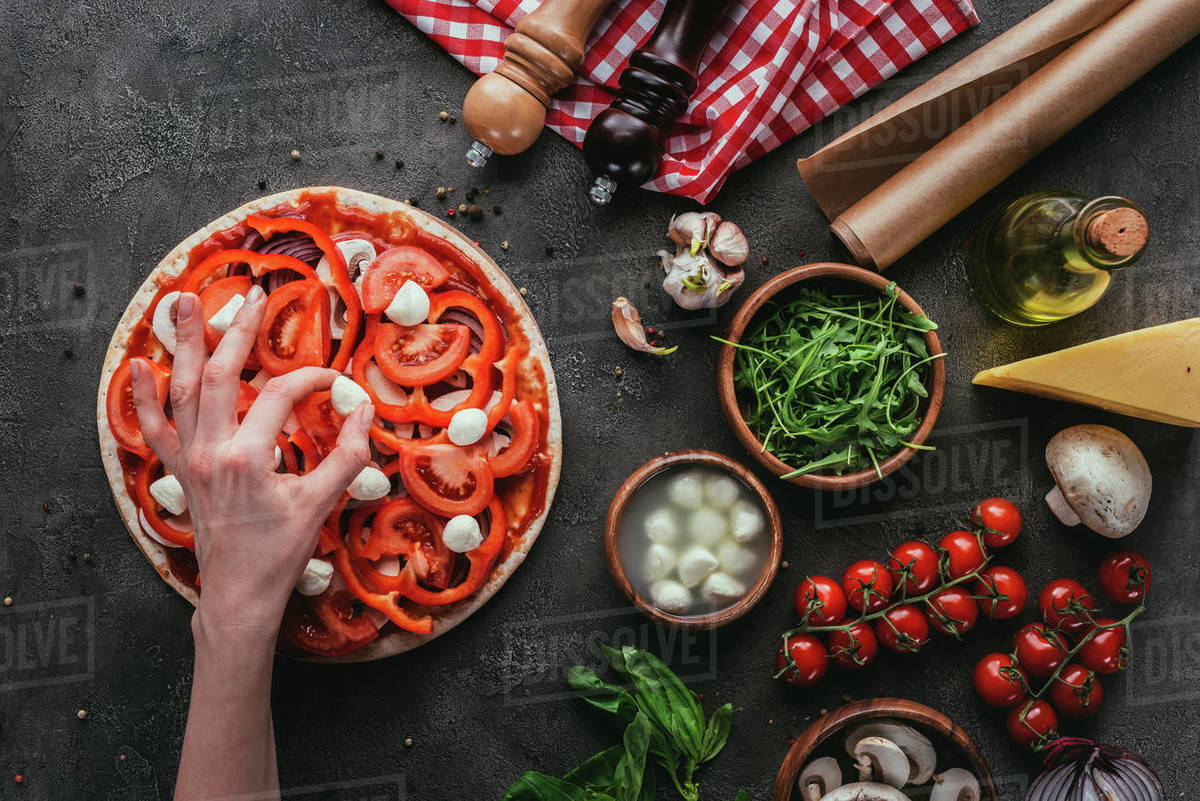 Cropped shot of woman spreading mozzarella pieces onto pizza on ...
