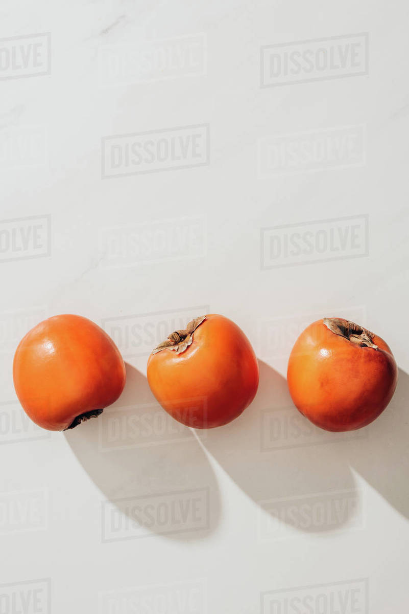 top view of three ripe persimmons on white - Royalty-free Stock Photo ...