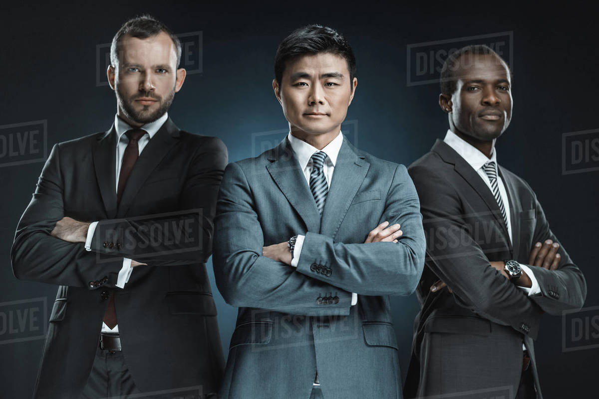 portrait of multicultural group of businessmen in suits looking at ...
