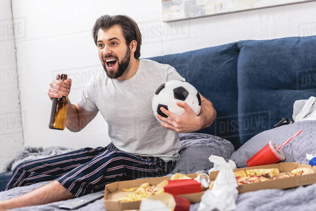 Handsome loner watching football game with beer and screaming in ...