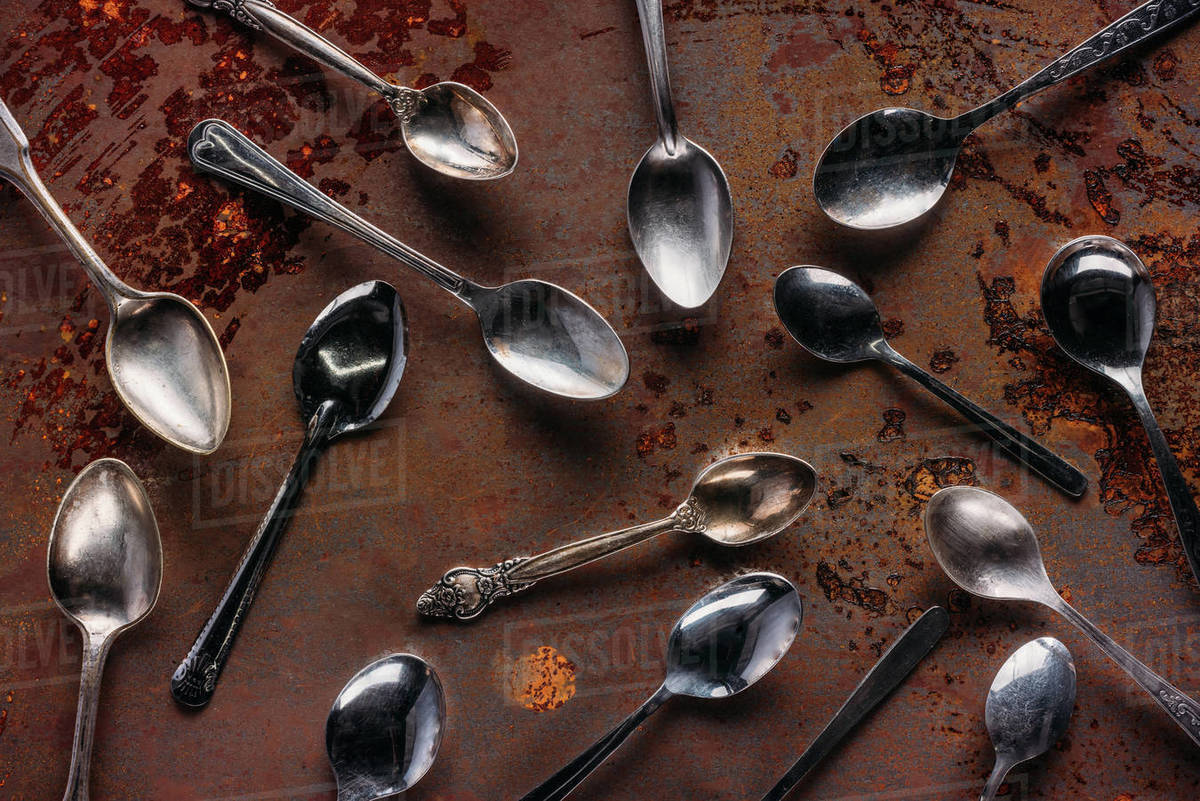 Vintage metal spoons on rusted background - Stock Photo - Dissolve