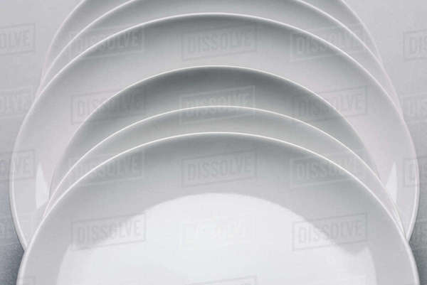 White plates in a row on white table - Stock Photo - Dissolve