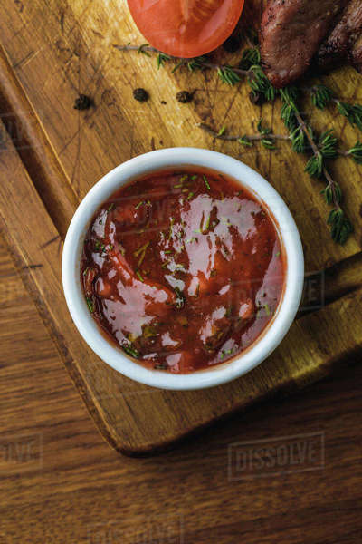 Top view of bbq sauce in bowl and delicious roasted meat with tomato on ...