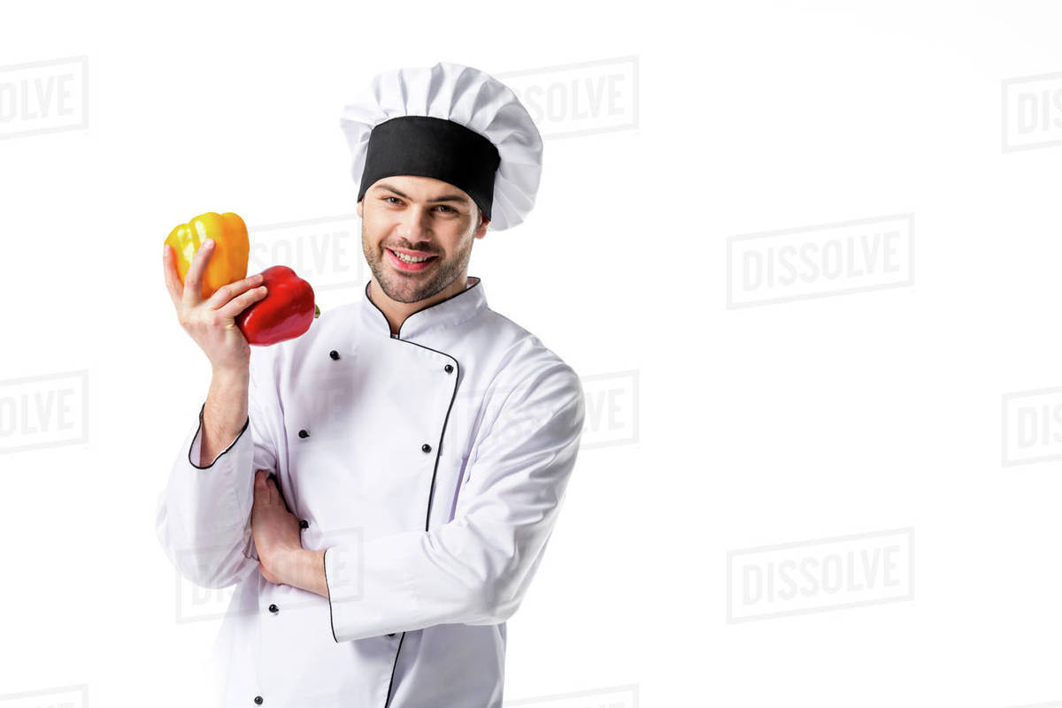 Smiling chef in uniform with fresh bell peppers in hand isolated on ...