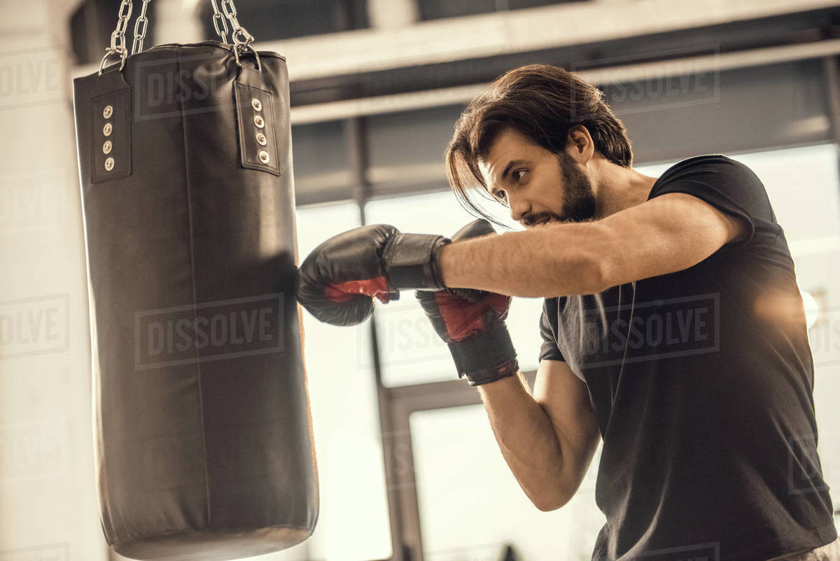 Side view of handsome young man boxing in sports center - Royalty-free ...