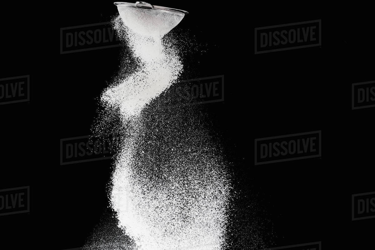 Sieve with falling flour isolated on black - Stock Photo - Dissolve