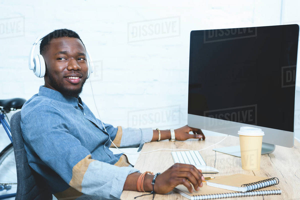 Young man in headphones working by table with computer - Royalty-free ...