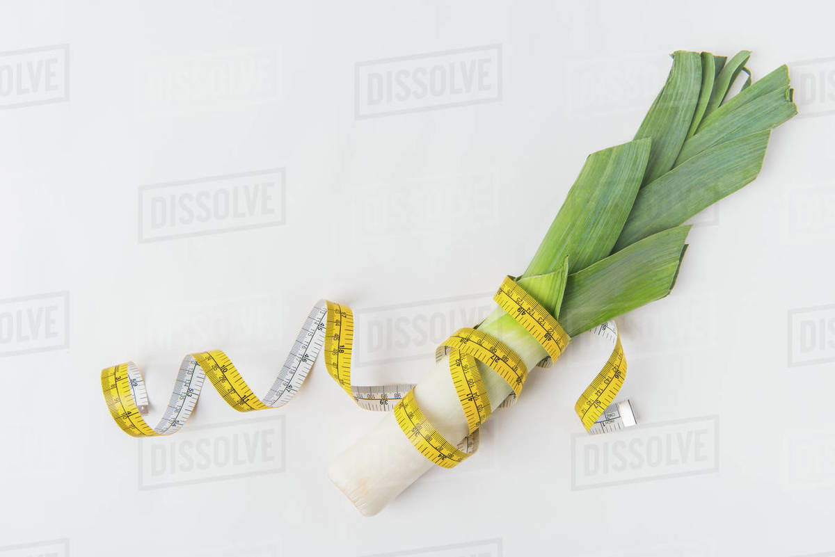 Raw green leek with measuring tape isolated on white background ...