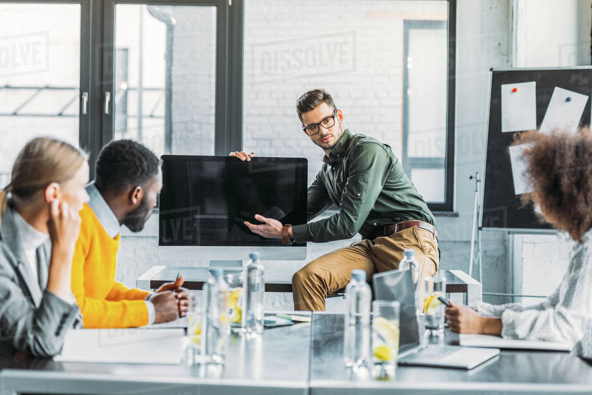 Multicultural businesspeople looking at computer screen during meeting ...