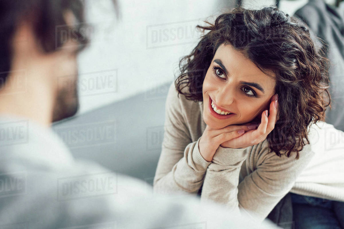Cropped image of smiling girlfriend looking at boyfriend at home ...