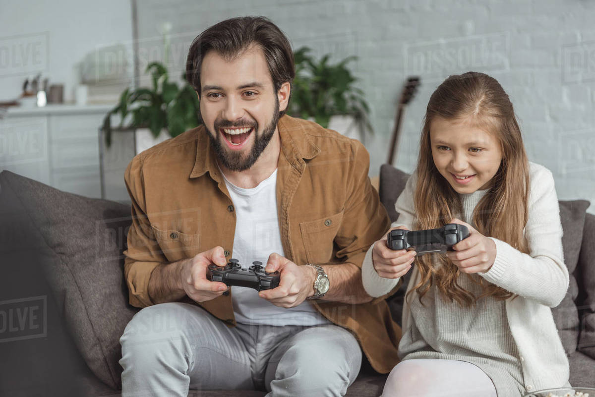 Happy father and daughter playing video game at home - Stock Photo ...