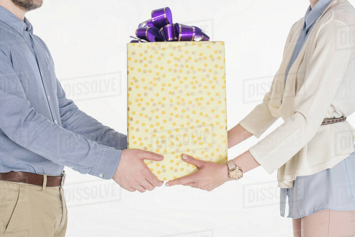 Side view of couple holding wrapped gift in hands together isolated on ...
