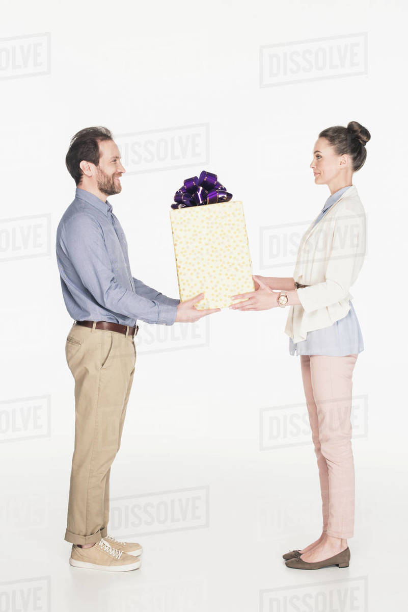 Side view of smiling man presenting wrapped gift to wife isolated on ...