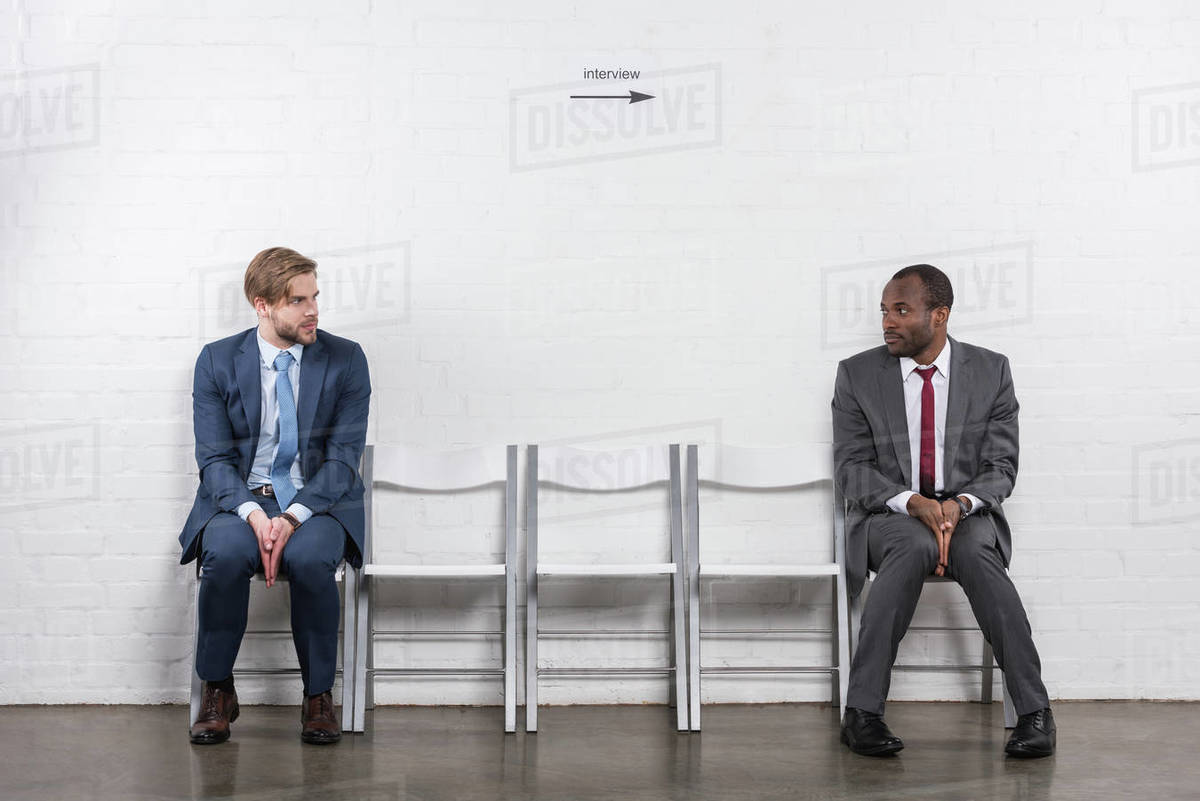 Scared multiethnic businessmen looking at each other while waiting for ...