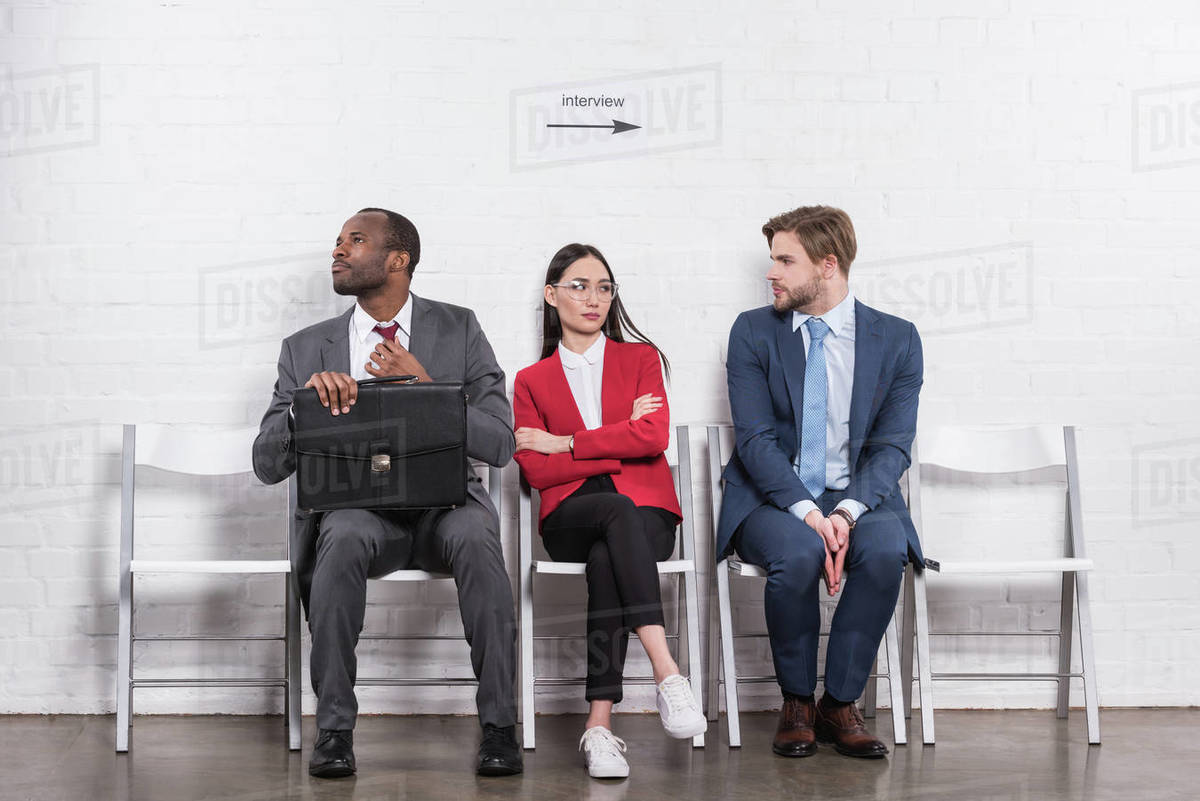 Multiethnic business people sitting on chairs while waiting for job ...