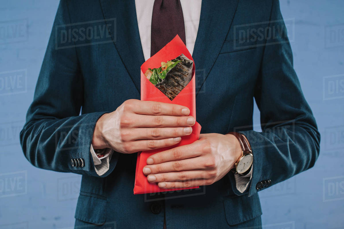 Cropped shot of businessman in suit holding doner covered in red paper ...