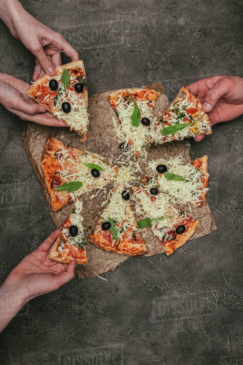 Close-up view of people eating pizza on dark background - Stock Photo ...
