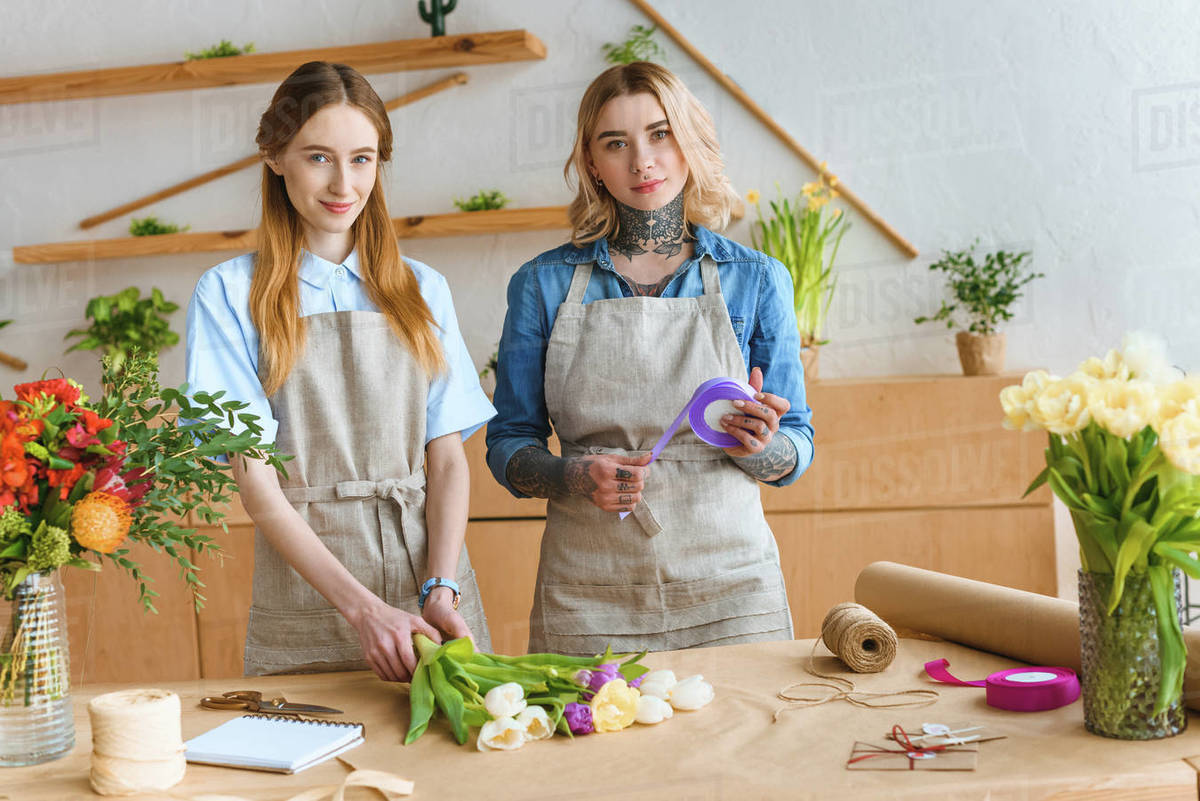 beautiful young florists working together and smiling at camera ...
